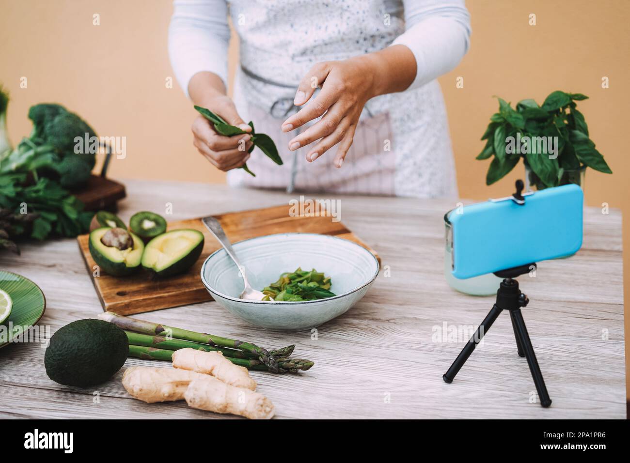 Young woman streaming online healthy food cooking lesson of green salad ...