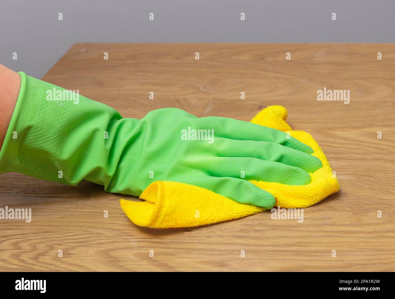 Hand in green glove wiping dust from wooden desk, cleaning wood table ...