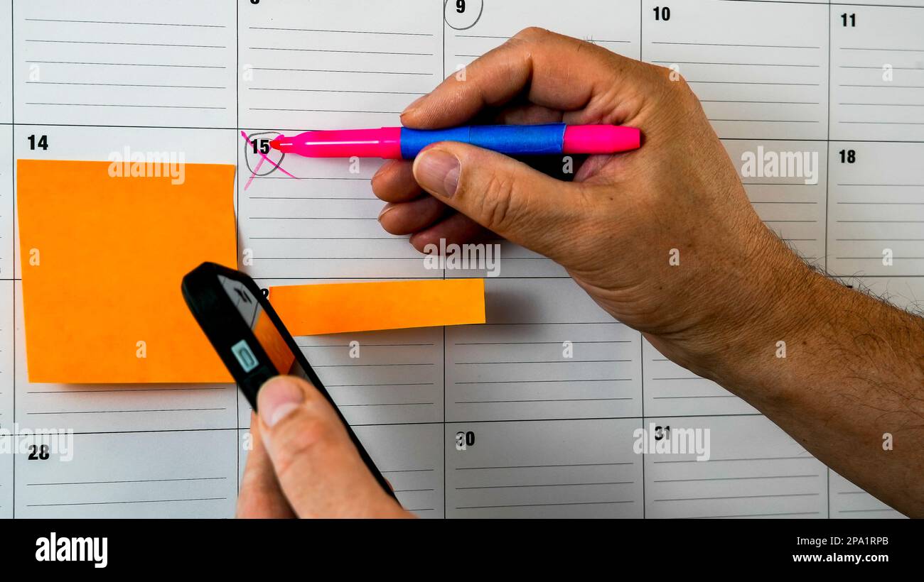 Hand holding phone and marking date in calendar with copy space Stock ...