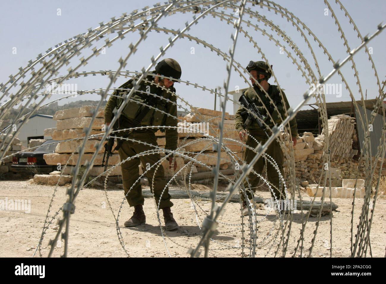Israeli soldiers place razor wire as Palestinians, not seen, protest ...