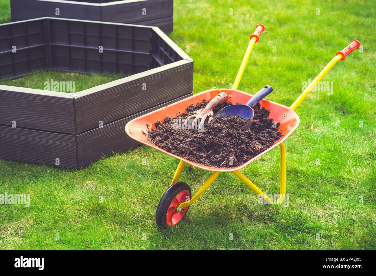 Garden barrow with soil and empty raised beds on grass prepared for ...