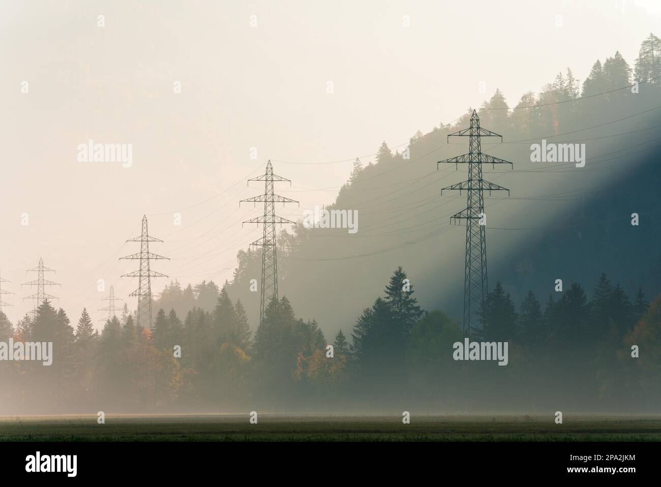 Power lines and lattice crosses on a hazy morning in a mountain valley ...