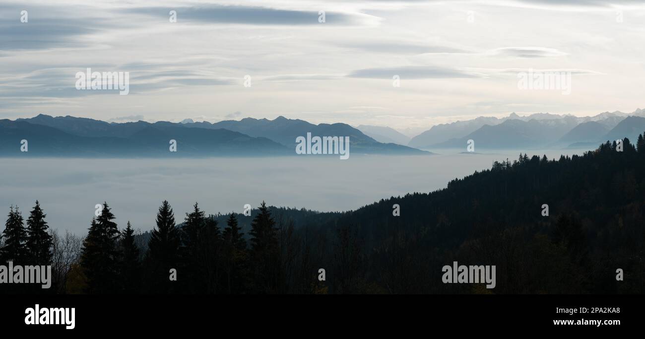 Rolling mountain ridges in a light hazy sky with fall color forest in ...