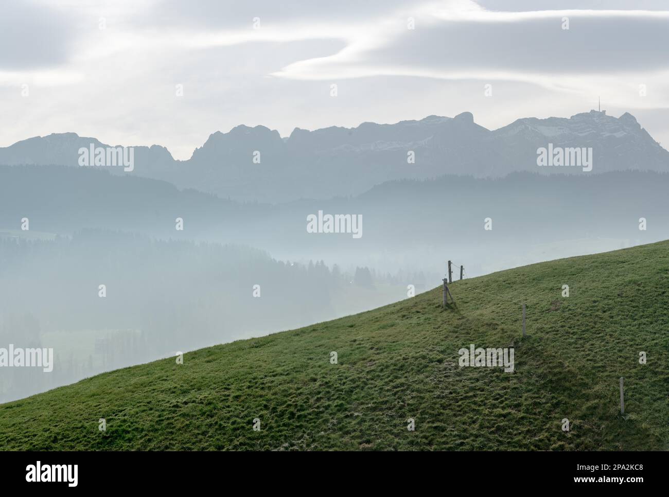 Rolling mountain ridges in a light hazy sky with fall color forest in ...
