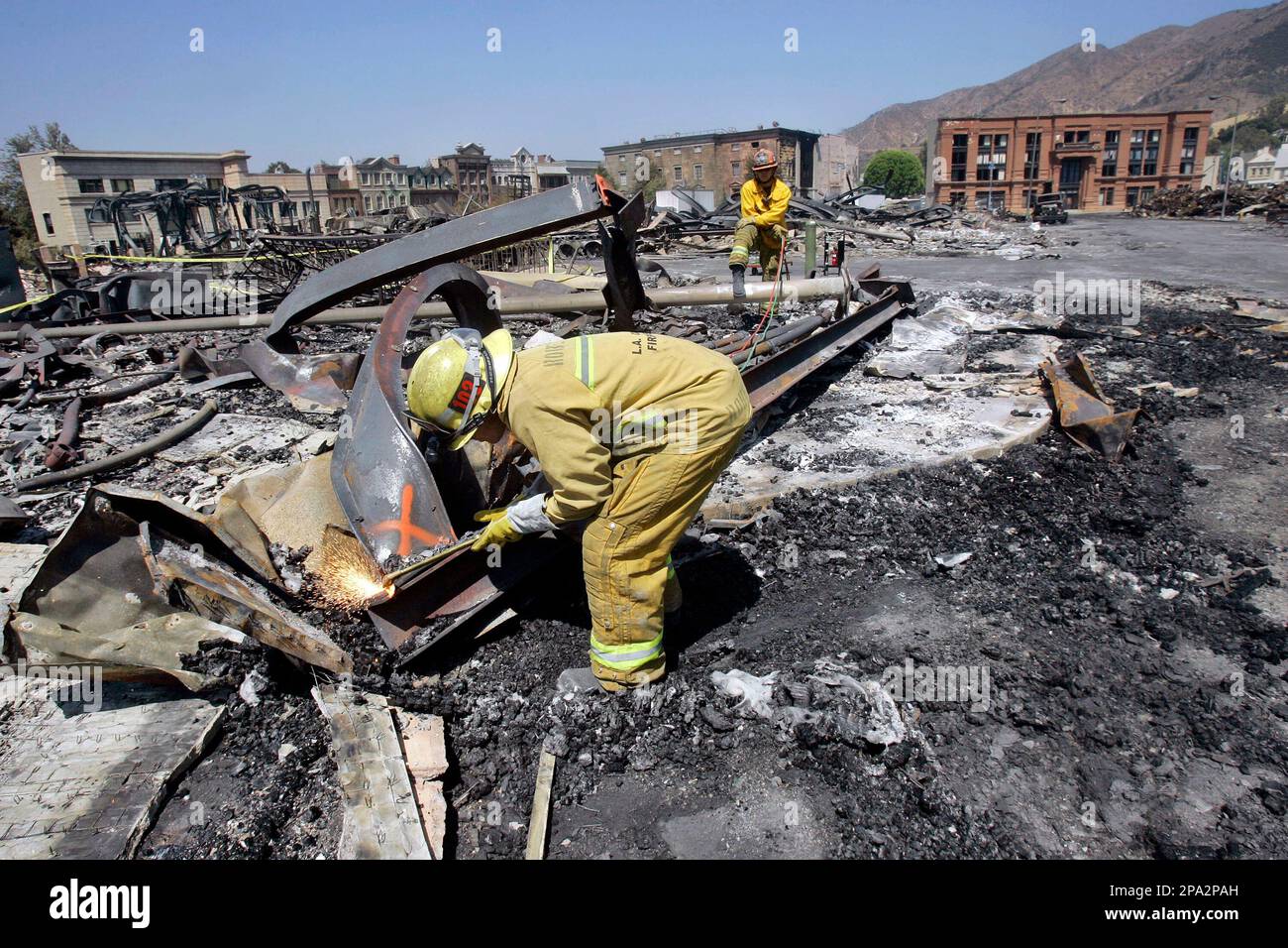 Los Angeles County firefighter Dustin Robertson uses a torch to cut a ...