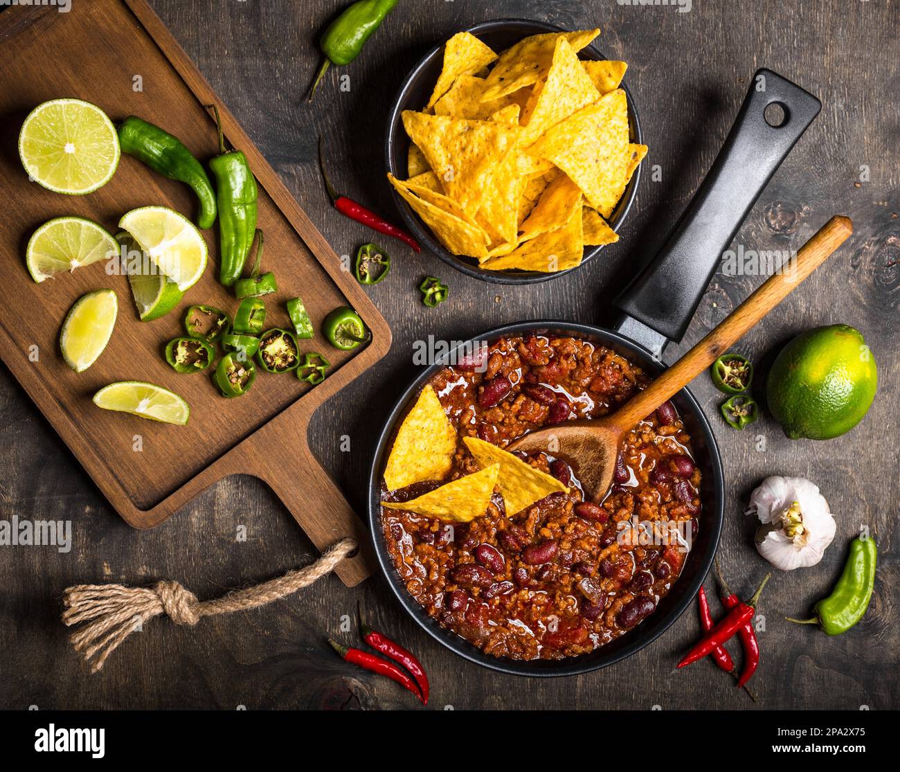 Chili con carne in frying pan on dark wooden background. Ingredients ...