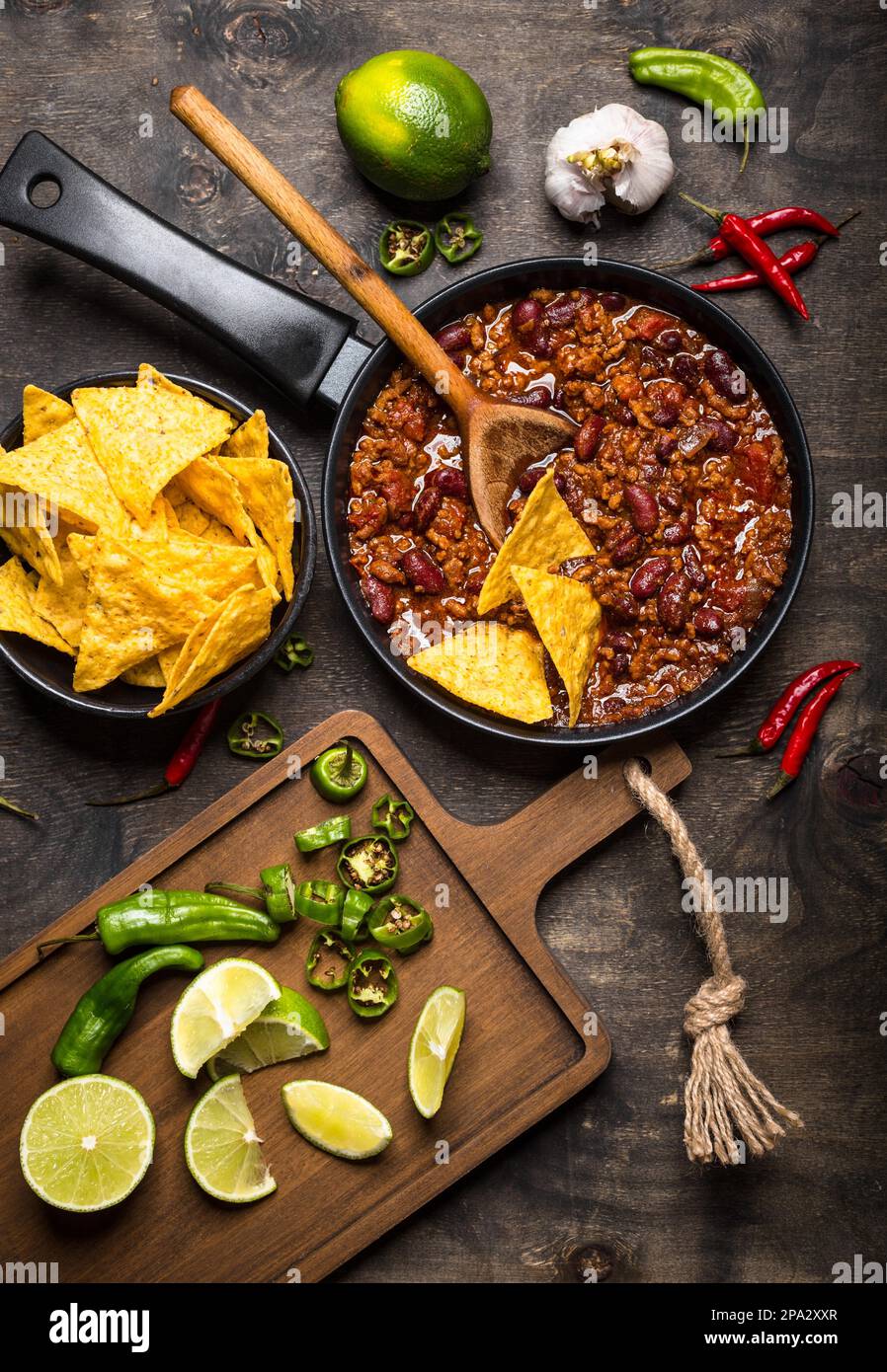 Chili con carne in frying pan on dark wooden background. Ingredients ...