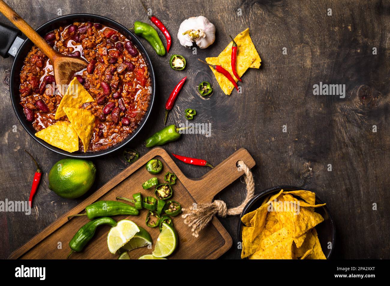 Chili con carne in frying pan on dark wooden background. Ingredients ...