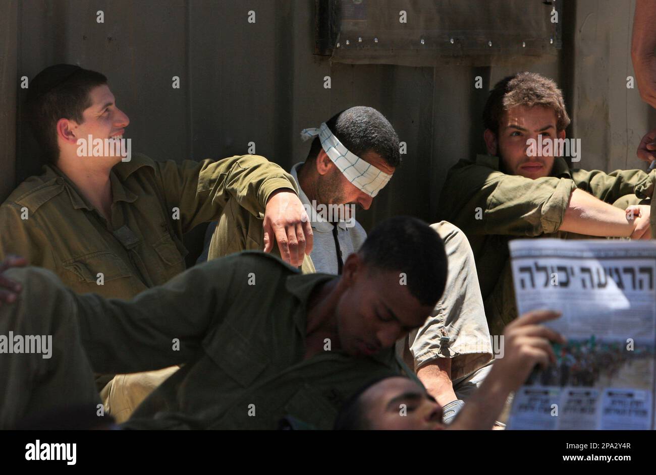 Israeli soldiers sit next to a blindfolded and handcuffed Palestinian ...