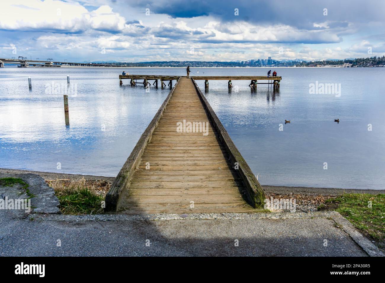 Clouds hang over a scene of Lake Washington with a highway and pier in ...