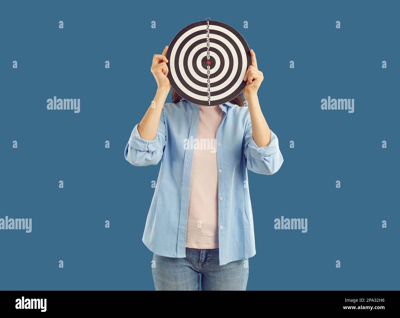 Woman holding shooting target in front of her face illustrating concept ...
