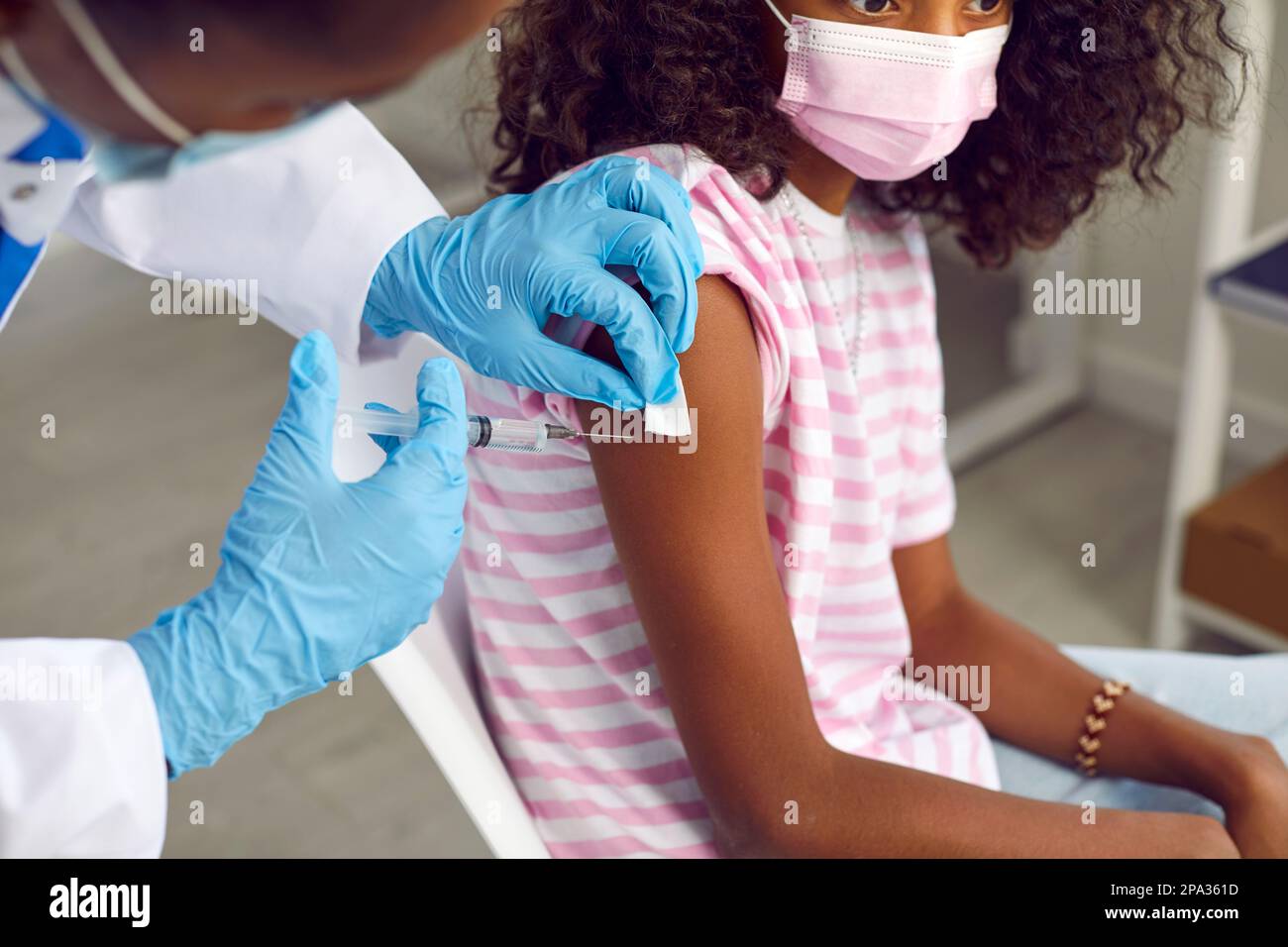 African American teenage girl receives flu shot from her family doctor ...