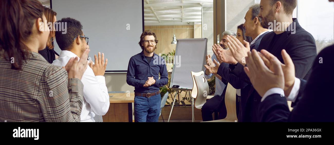 Group of people are greeting man coach in modern office clapping hands ...