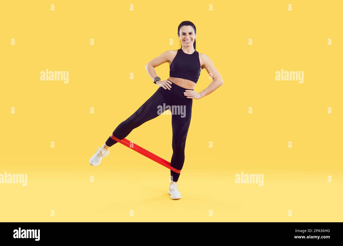 Fitness woman standing and stretching elastic band with legs isolated ...