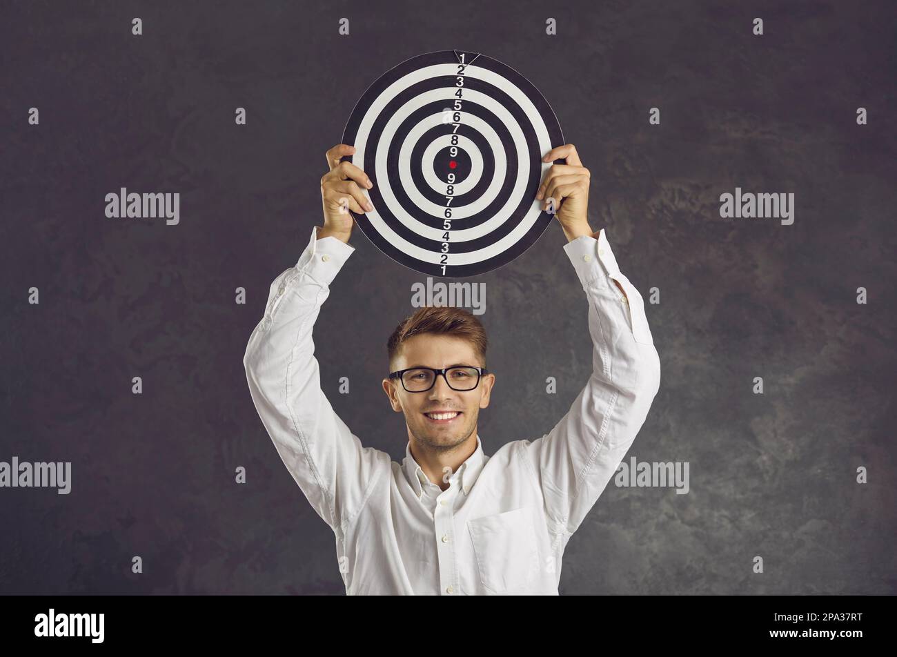 Happy young man holding shooting target to show concept of setting ...