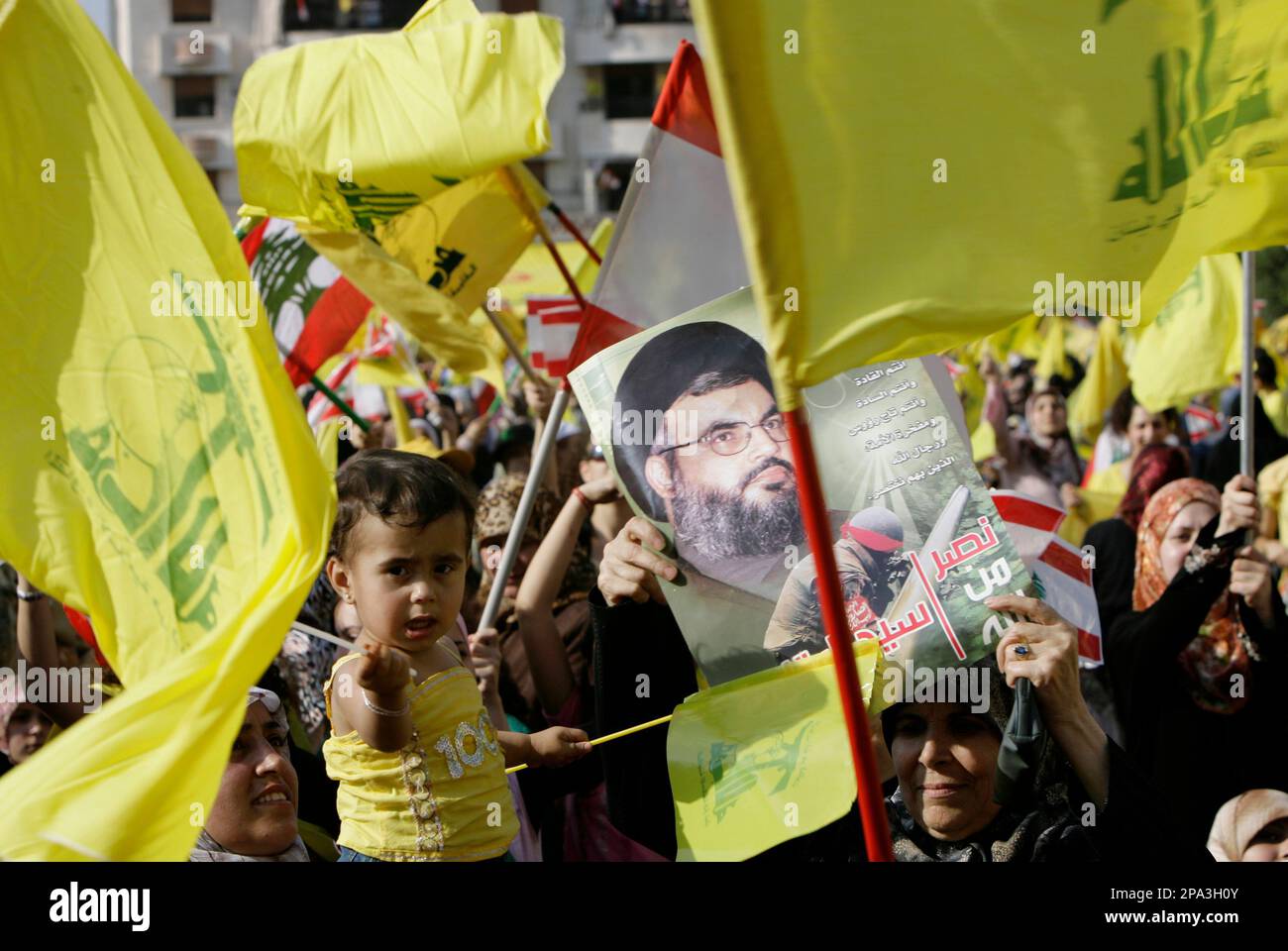 Supporters wave Hezbollah and Lebanese flags along with pictures of ...