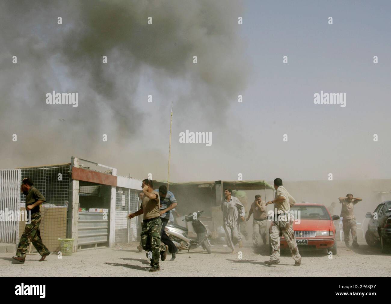 Iraqi men and Iraqi soldiers flee the site of a roadside bomb after it ...