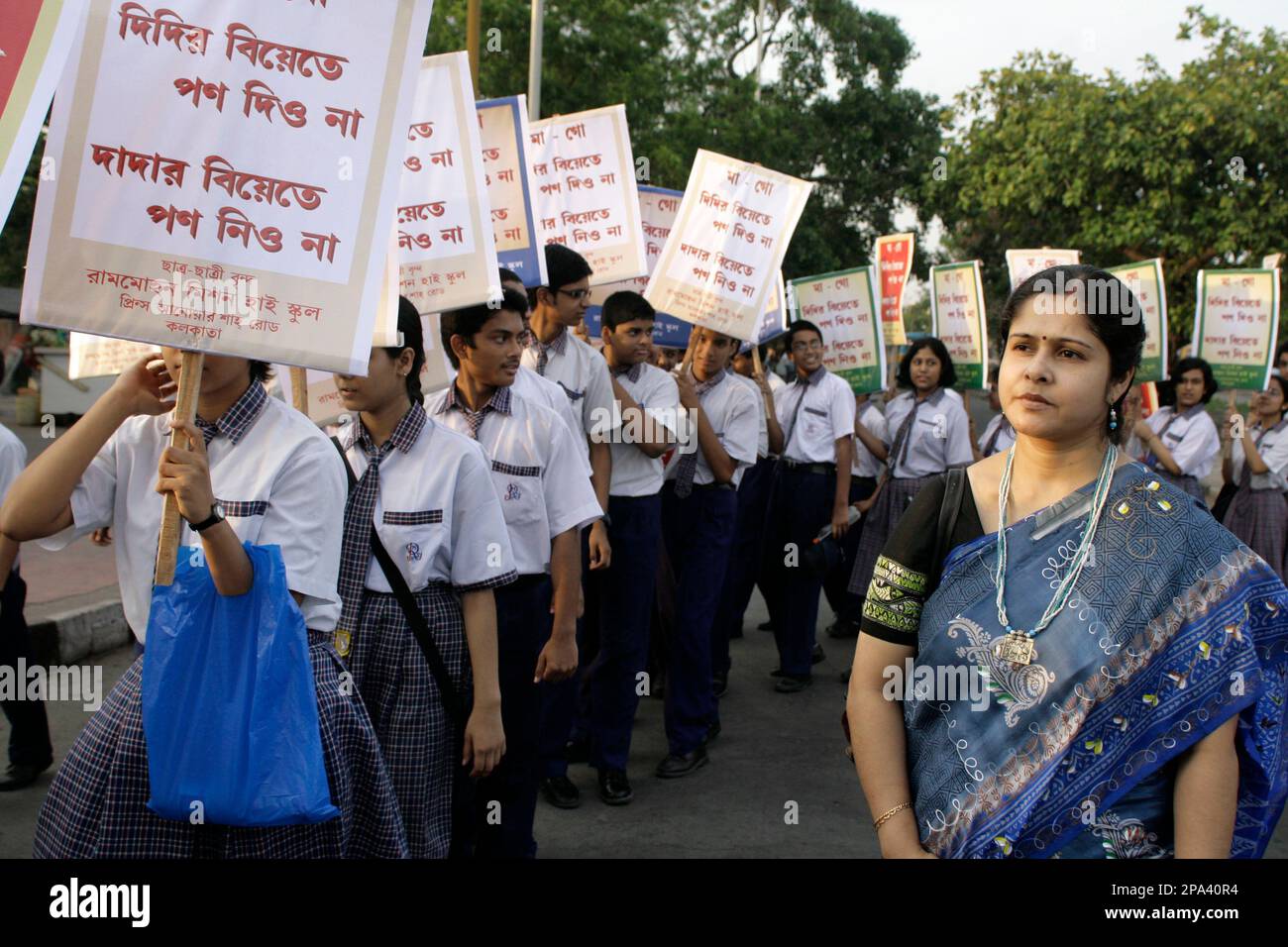 An Indian woman looks on as school girls and boys walk with anti dowry ...