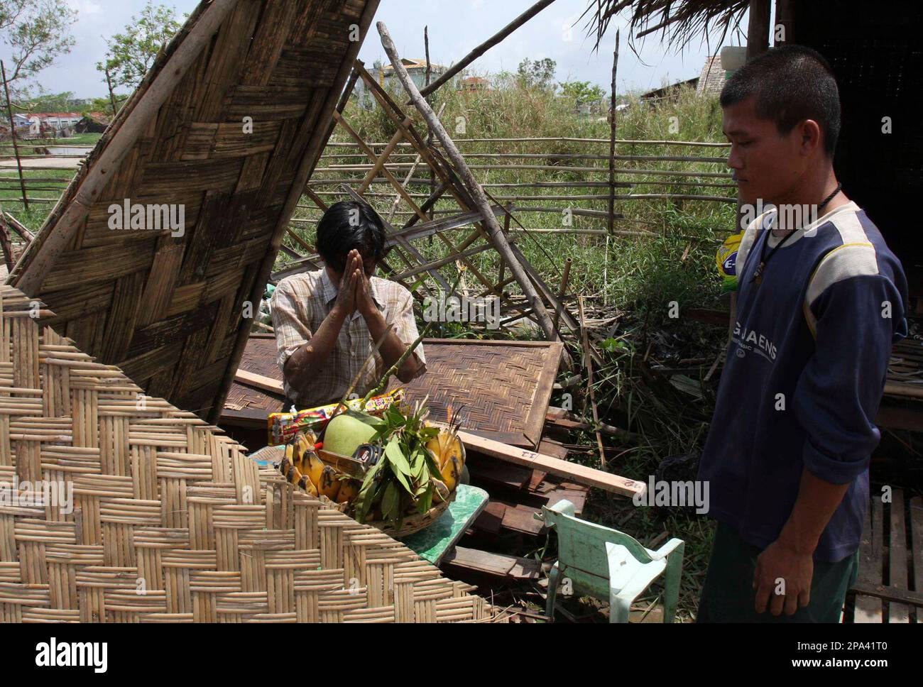 A Myanmar man prays in front of his damaged house which was destroyed ...