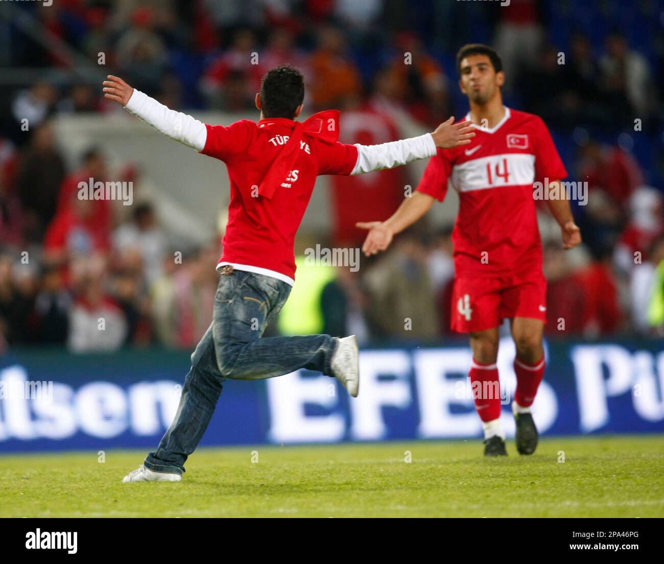 A supporter of Turkey runs over the pitch to Arda Turan, right, after a friendly match prior to ...
