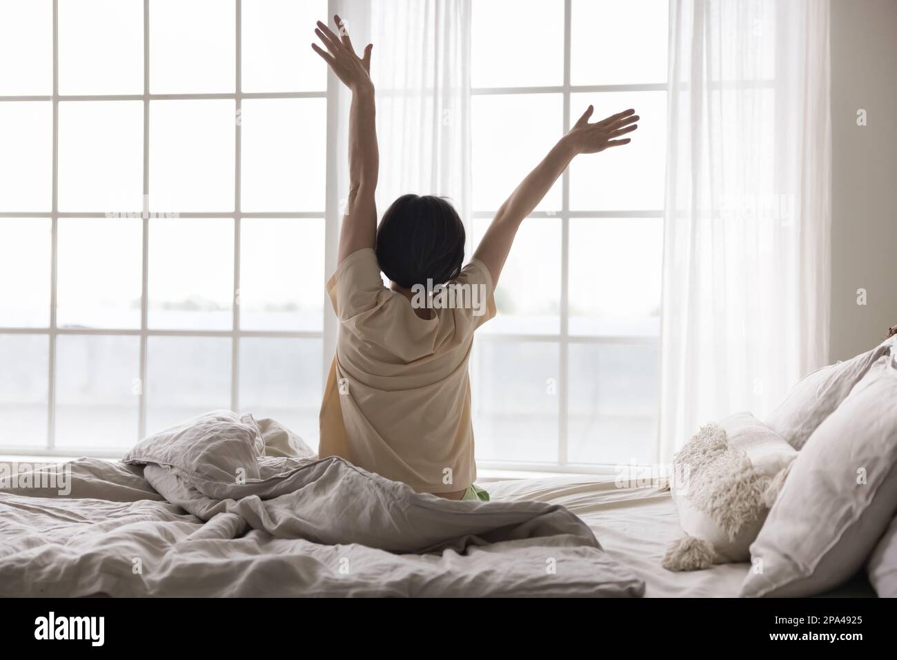 Satisfied relaxed middle aged lady sitting on bed, rising hands Stock ...