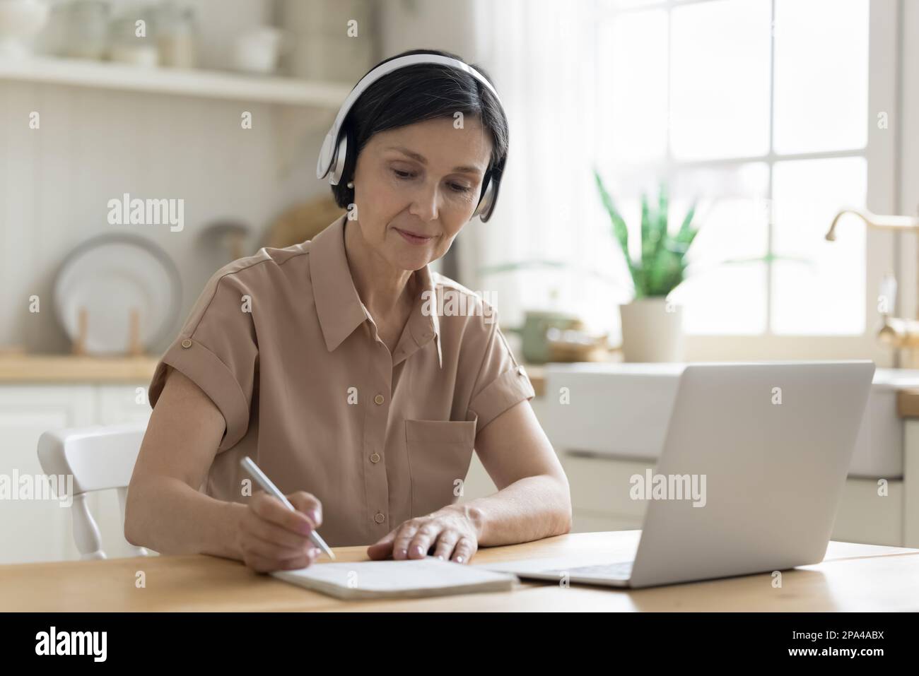 Focused mature student woman in wireless headphones watching learning ... Focused mature student woman in wireless headphones watching learning ...