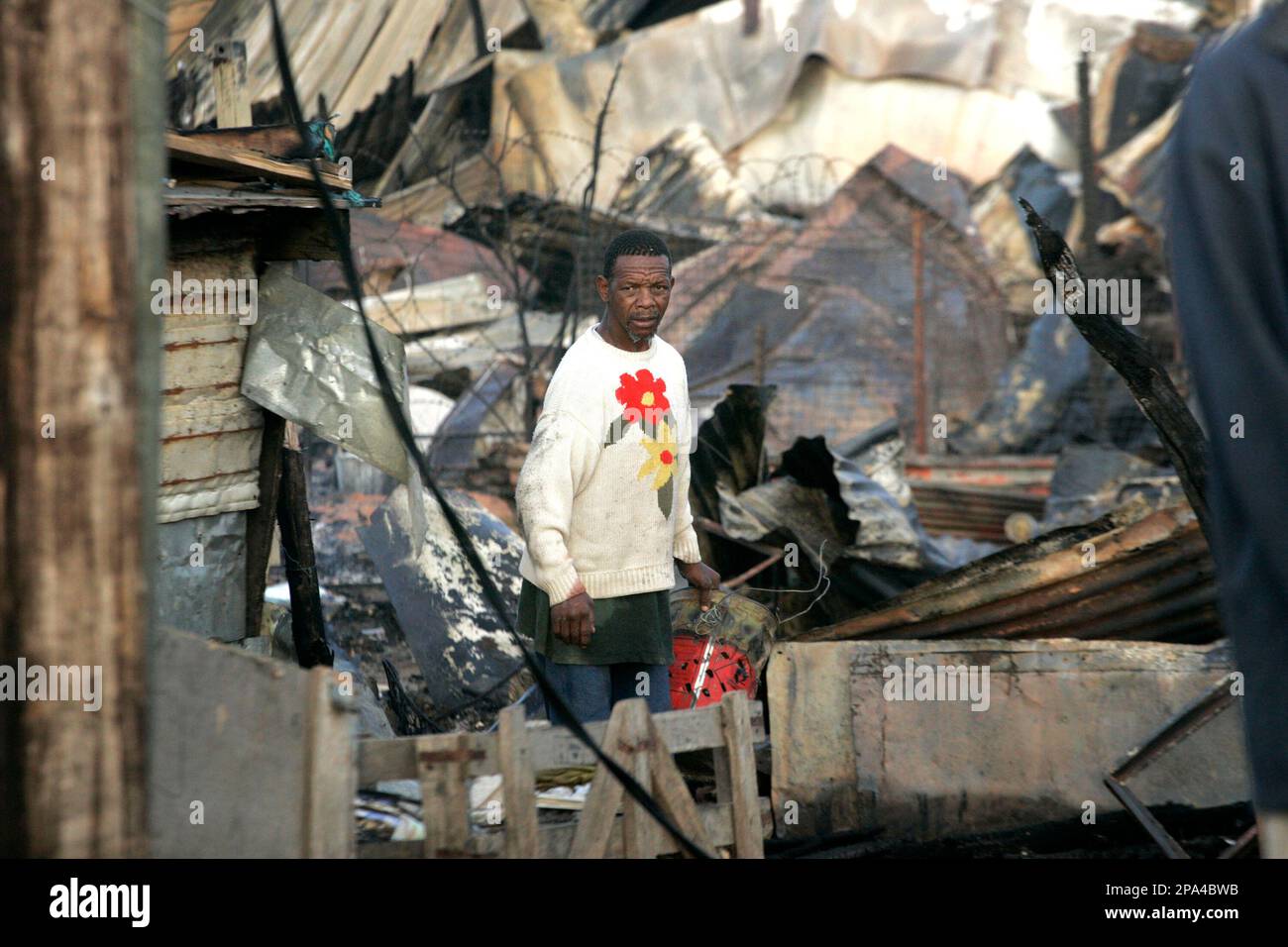 An unidentified man walks through burnt shacks during riots in the ...
