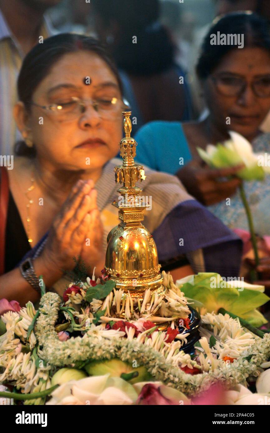 An Indian devotee looks at a relic of Buddha inside a gold urn at a ...