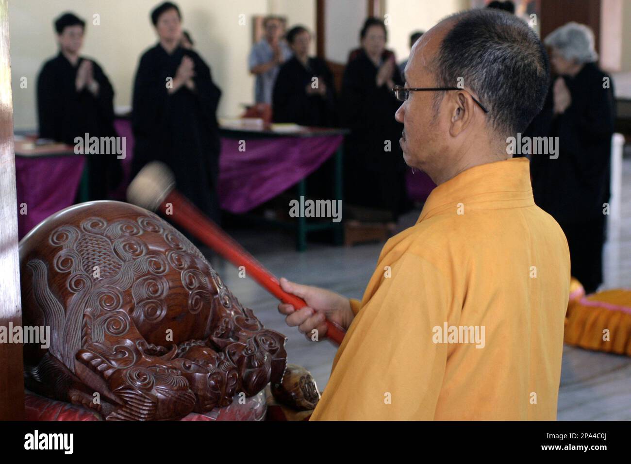 A Chinese priest beats a traditional instrument as others pray at a ...