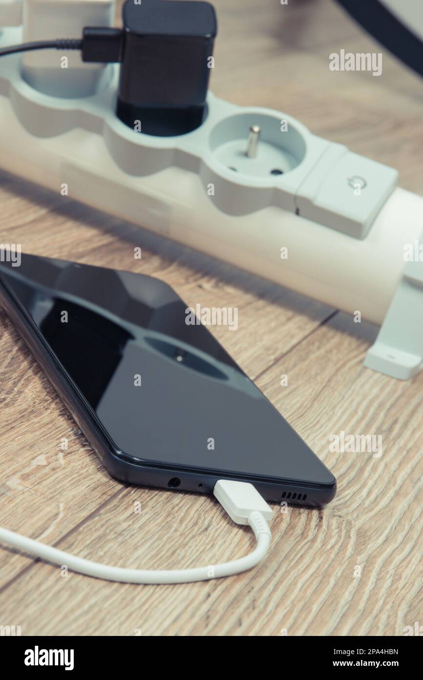 Smartphone, mobile phone and chargers connected to electrical power ...