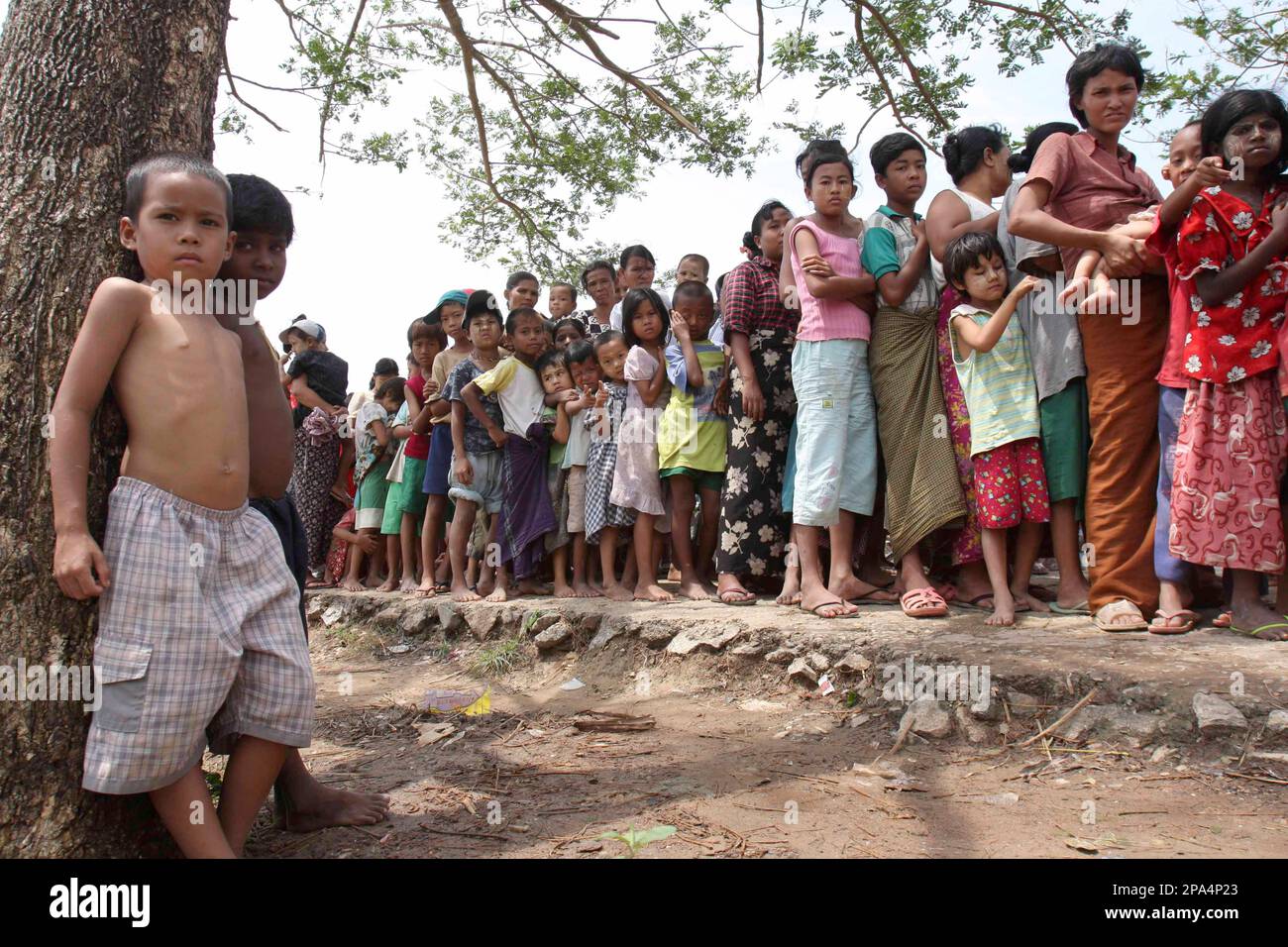 Myanmar cyclone survivors wait in line for rice donations on the ...