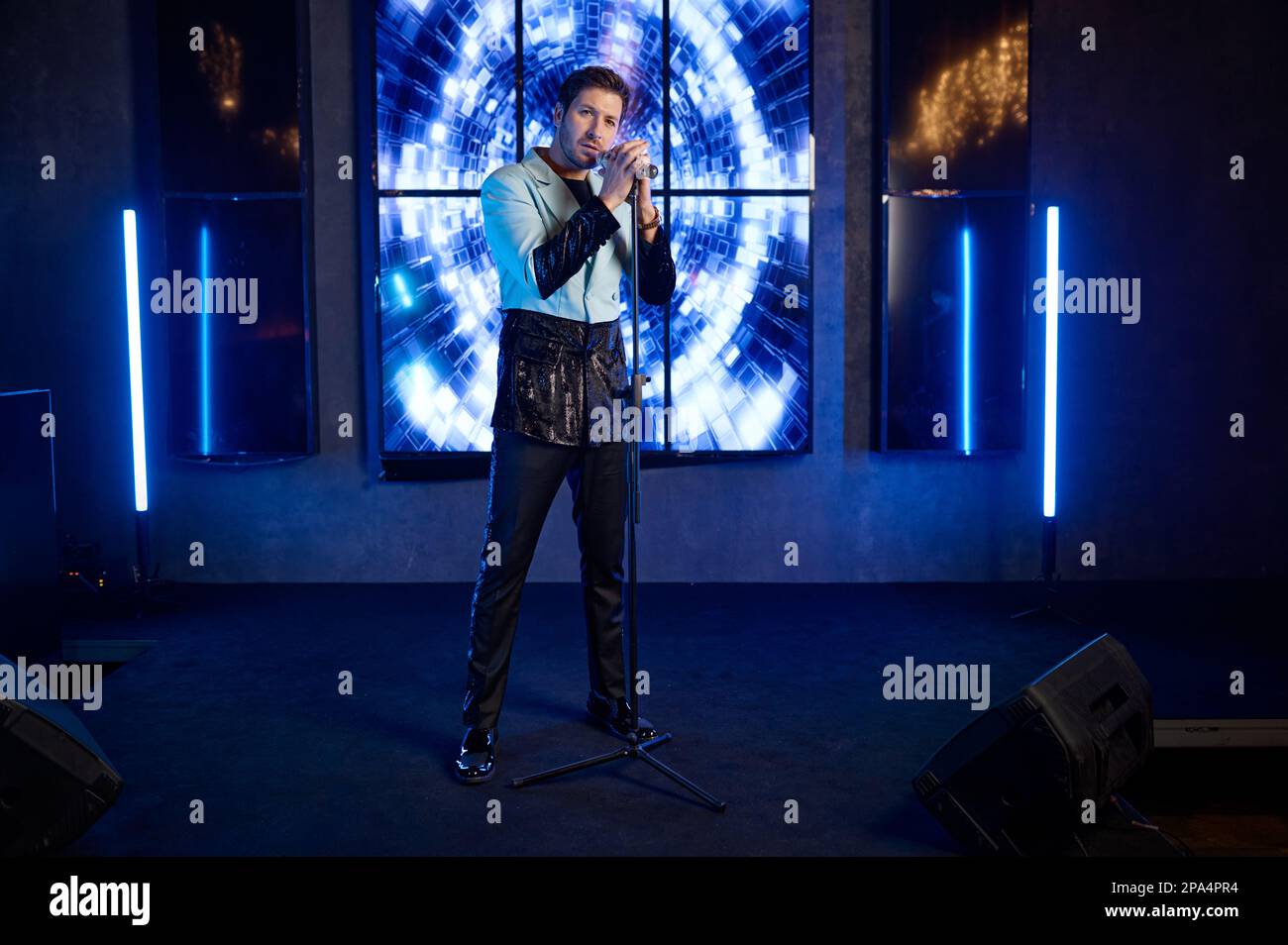 Portrait of handsome attractive singer singing in microphone on stage ...