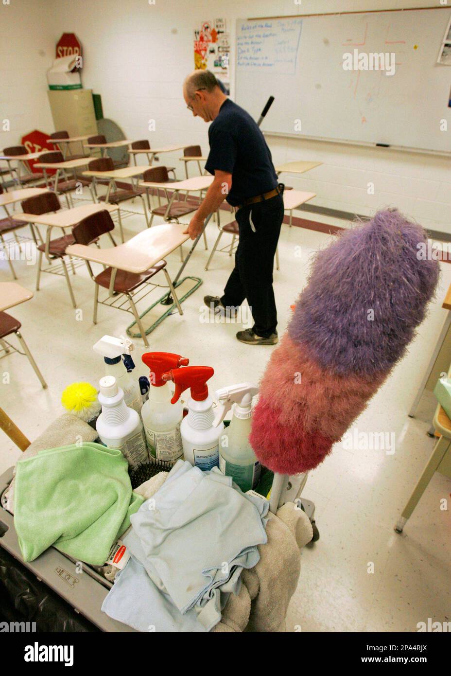 School custodian Bob Butler uses a micro-fiber dust mop as he cleans a ...