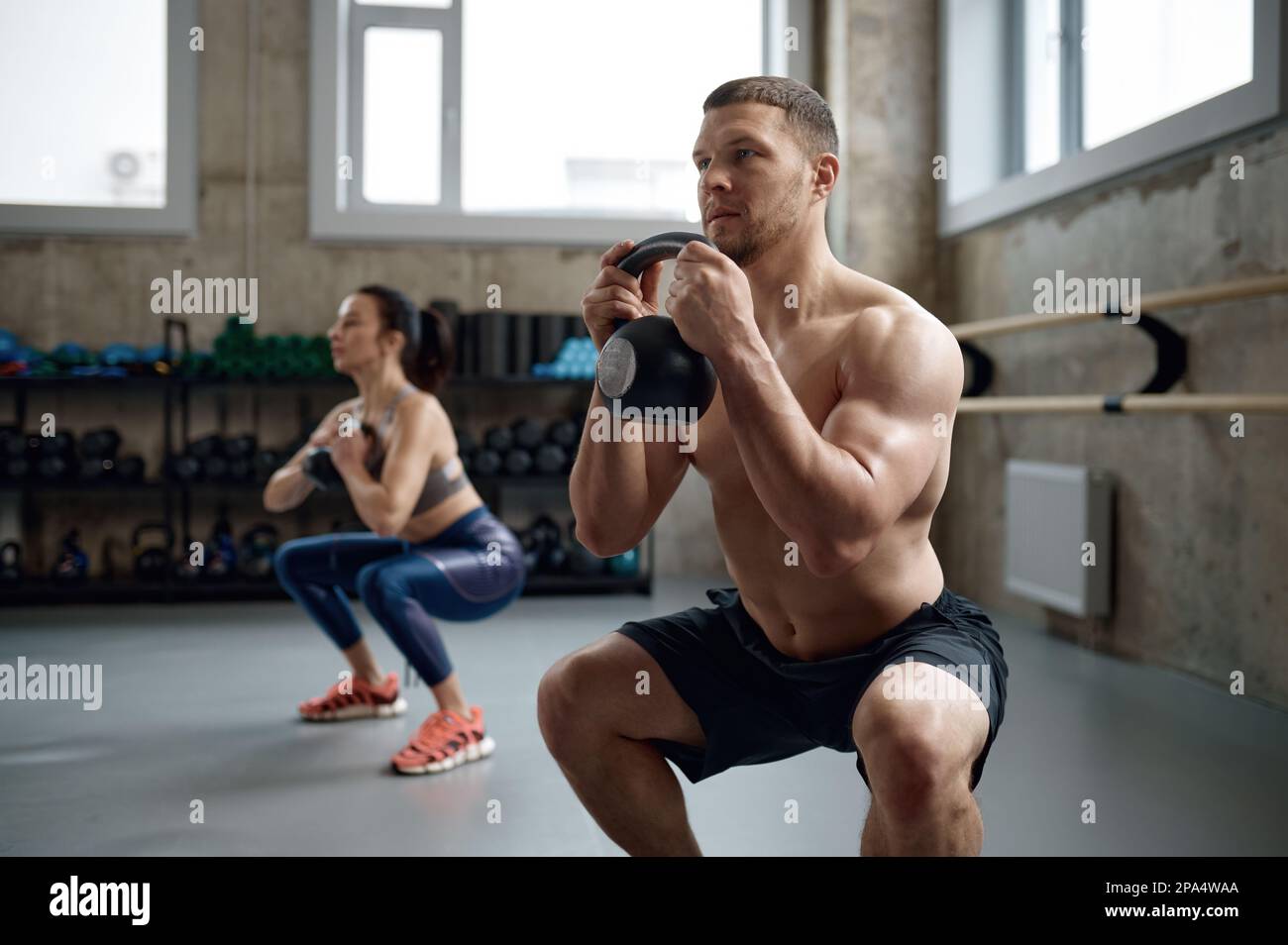 Man and woman with good physique holding heavy kettle bell Stock Photo ...