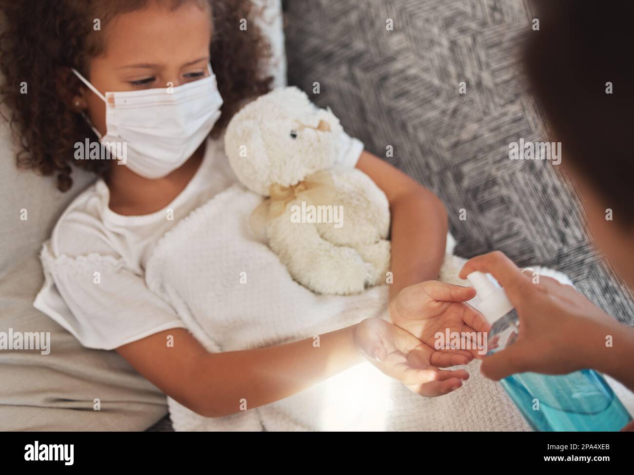 Cleaning hands with sanitizer during covid, caring mother showing good ...