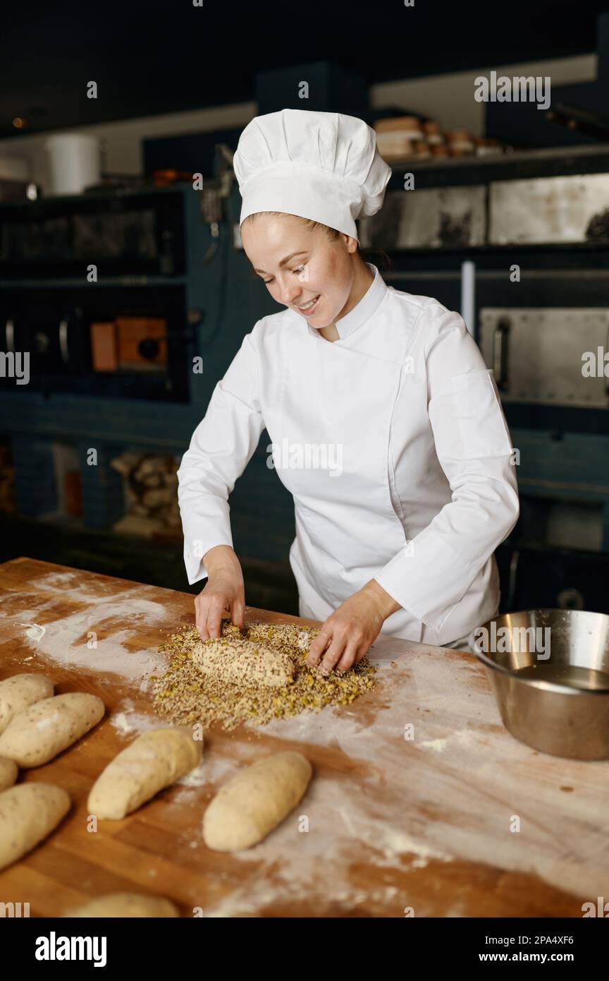Portrait of positive female baker shaping bread bagels with seeds Stock ...