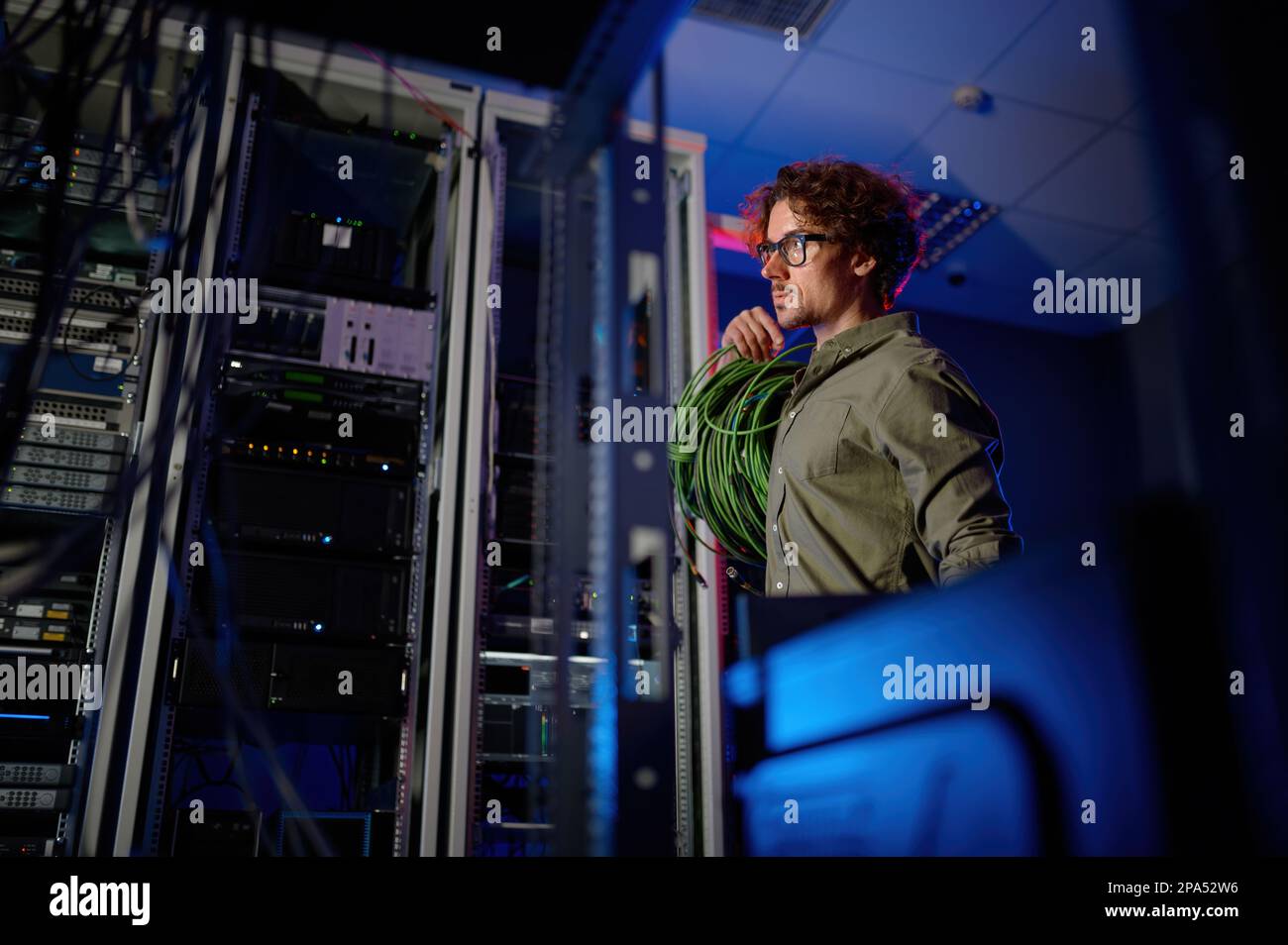 Data center engineer with many optic wires cables walking next to computer racks Stock Photo - Alamy