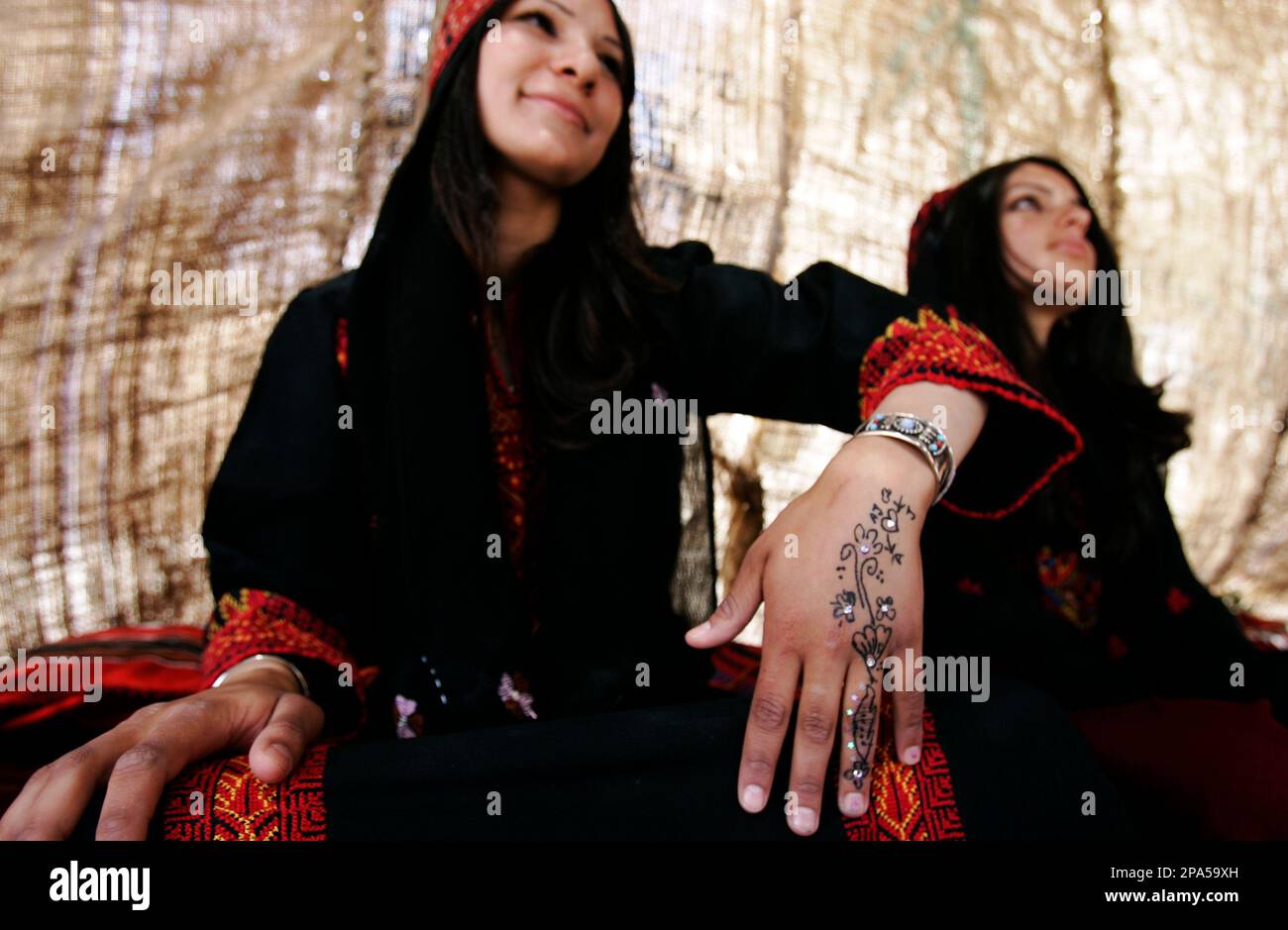 A Palestinian woman wearing traditional Arabic dress shows her hand ...