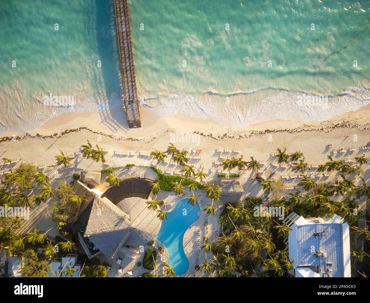 Aerial view of a sandy beach with palm trees, small houses. Clear warm ...
