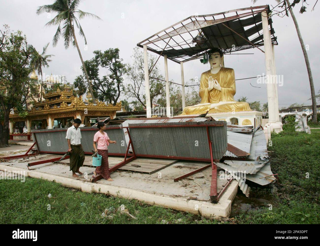 Myanmar people walk past at a damaged temple after cyclone Nargis hit ...