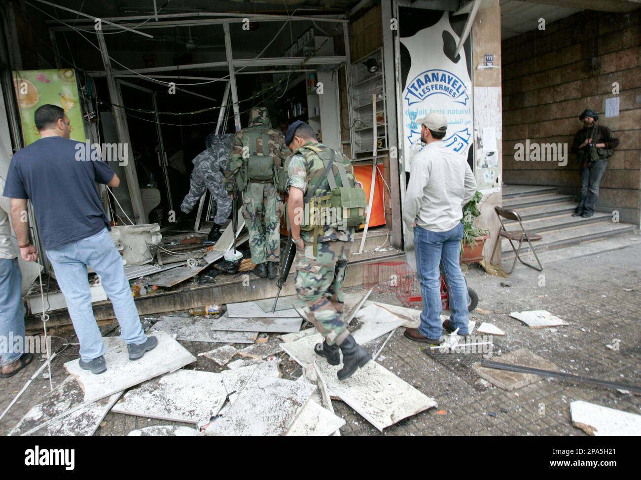 Lebanese army check a damaged shop as a Hezbollah militant, right, is ...