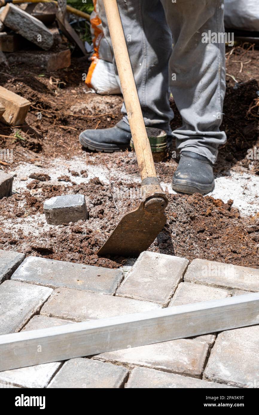 Brazilian using a hoe to prepare the soil for laying concrete blocks ...