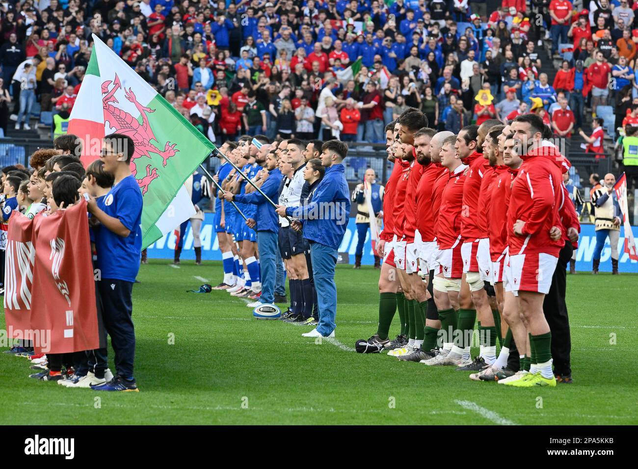 The Italy and Wales squads line up for the national anthems during ...