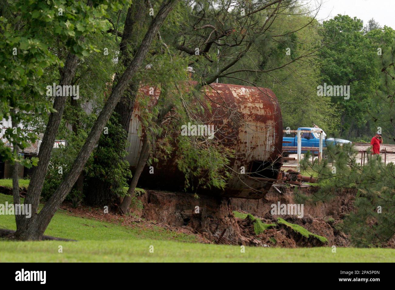 Dirt and sod fall away from under a rusty old tank into a giant ...