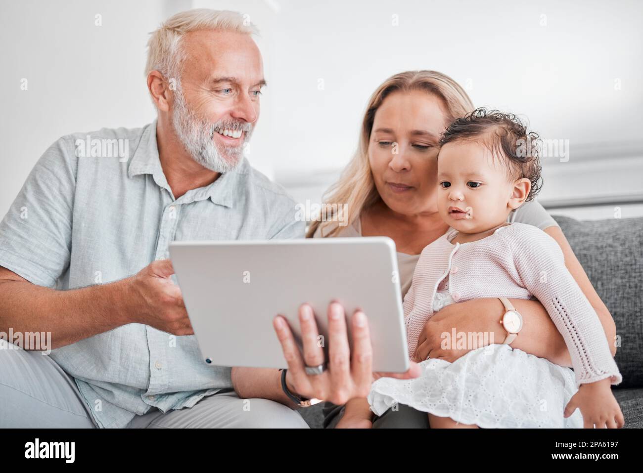 Family, tablet and baby with grandparents on sofa in home on social ...