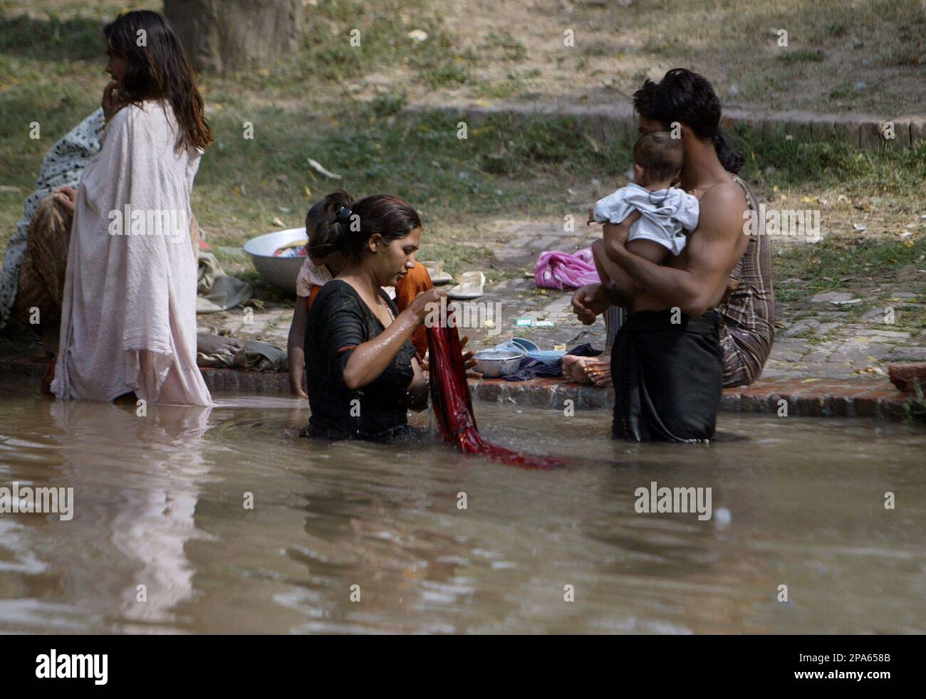 A Pakistani family cool off in a canal to take a reprieve from the heat ...