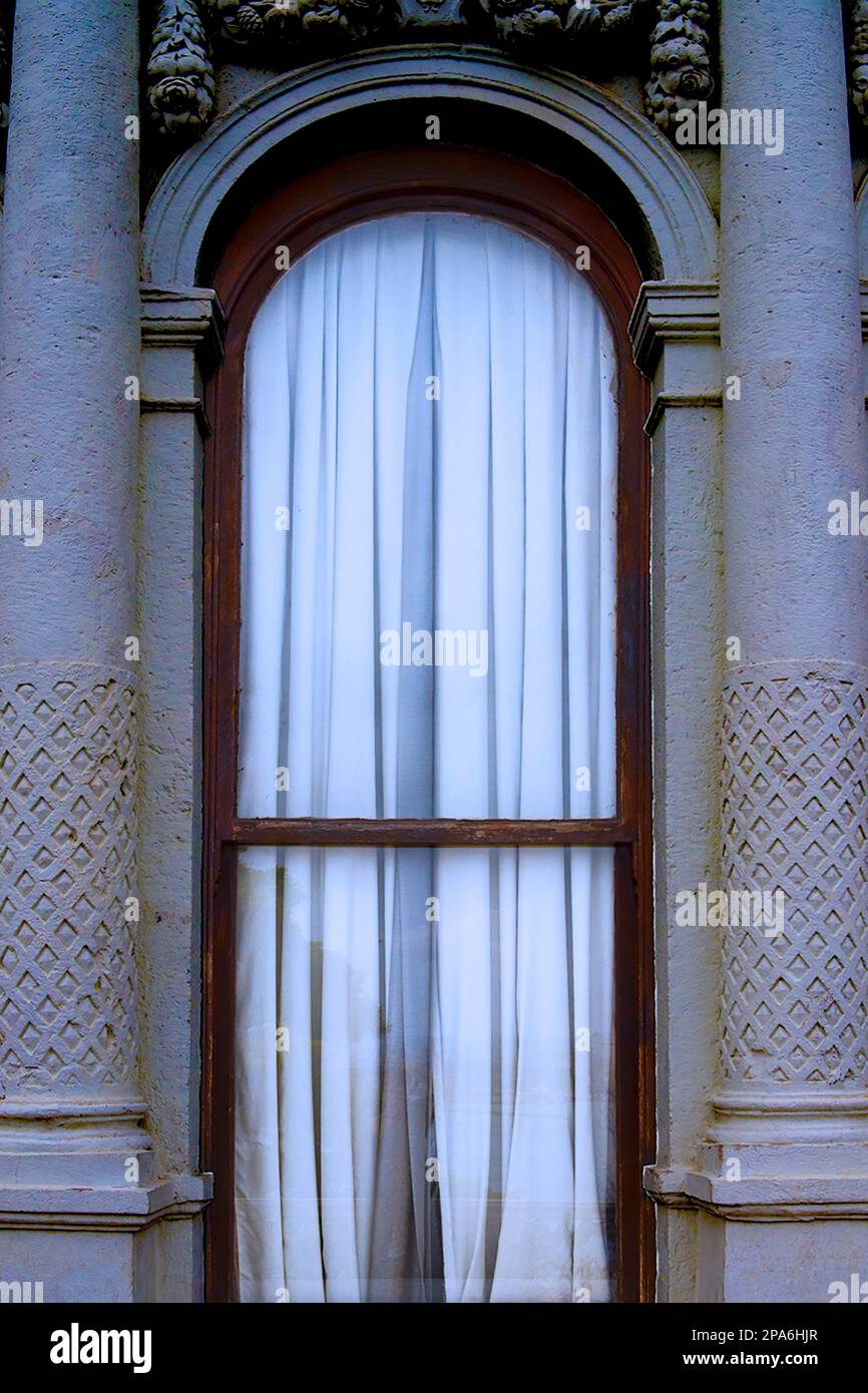 An exterior shot of an old building, featuring a small window with the ...