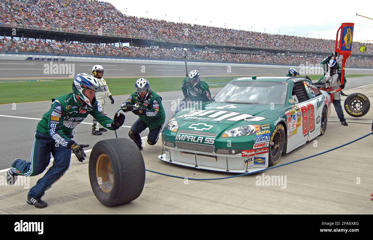 Pit crew members work to refuel and change the tires on NASCAR driver ...