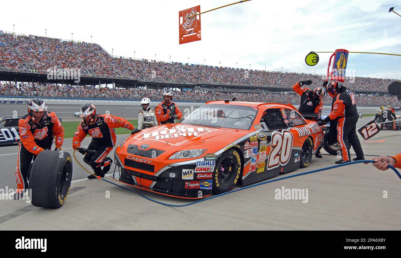 Crew members work to change the tires and refuel NASCAR driver Tony ...