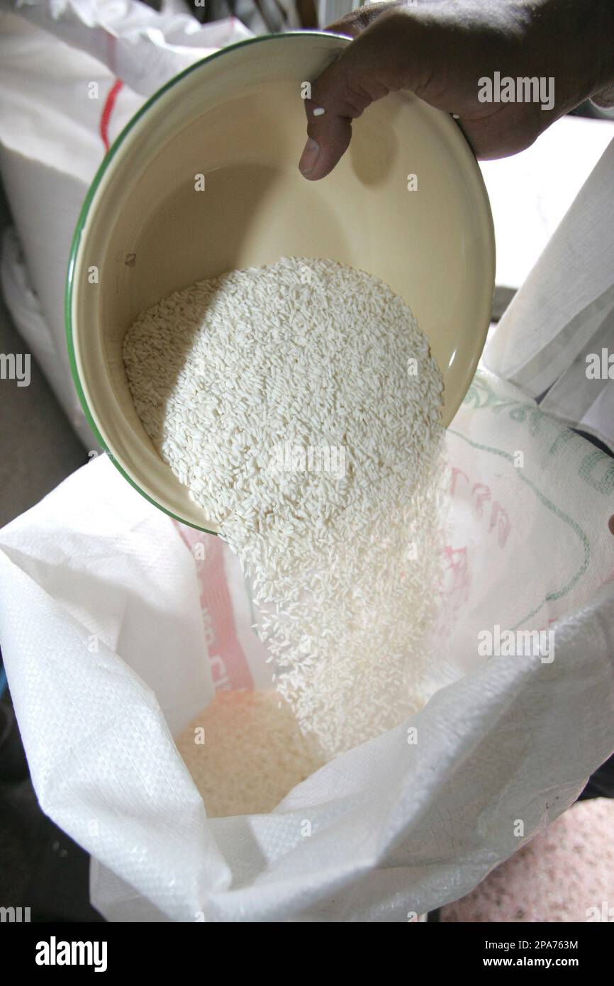 A Thai merchant weighs rice in a scale in his rice shop in Bangkok on ...